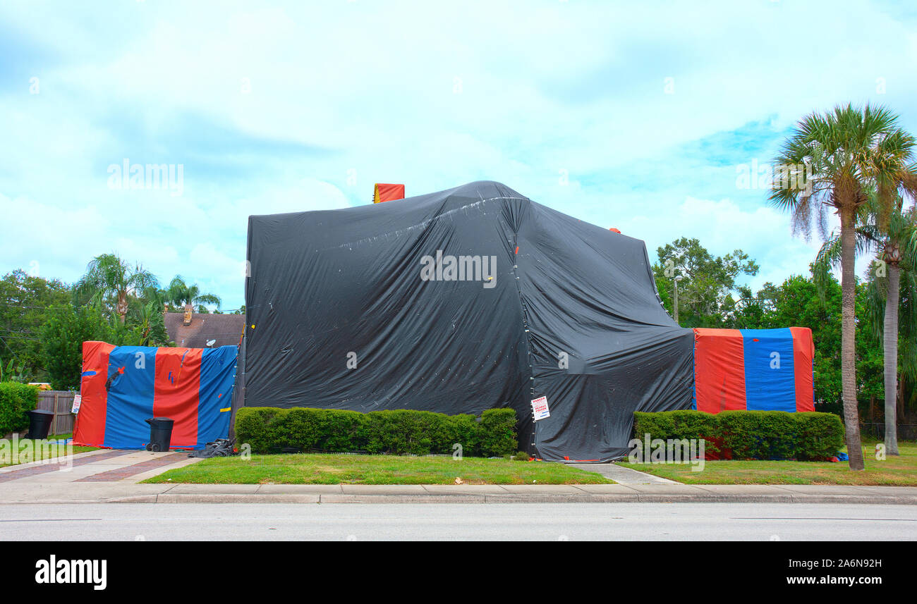 Tented large two story house with palm trees in the yard that is being ...