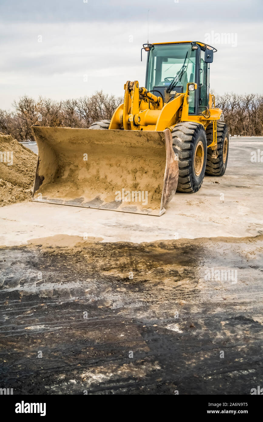 Focus on a yellow bulldozer with dirty bucket and wheels at a ...