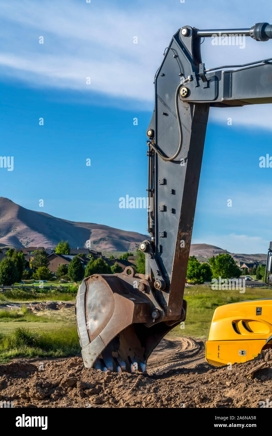 Metal arm and bucket of a yellow excavator digging soil at a ...