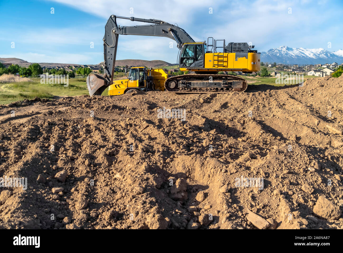 Yellow construction vehicles at a construction site against mountain ...