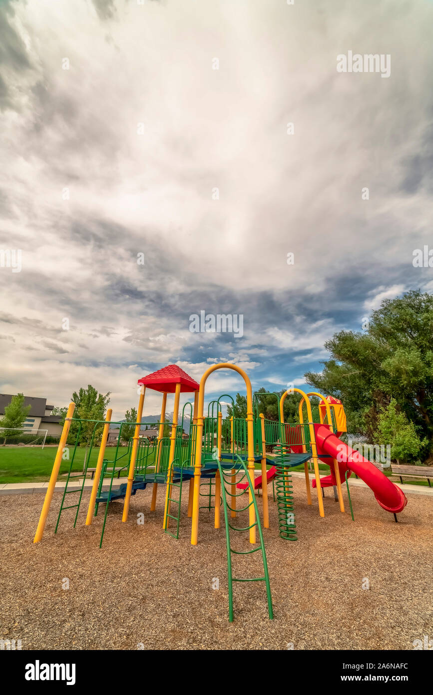 Focus on the colorful playground at a park with blue sky and clouds ...