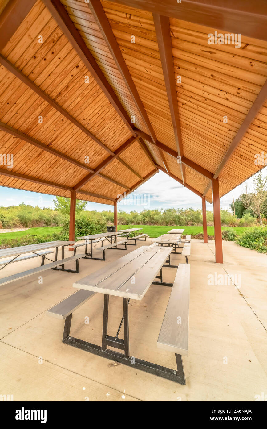 Row of white tables with seats under a pavilion with brown ceiling at a ...