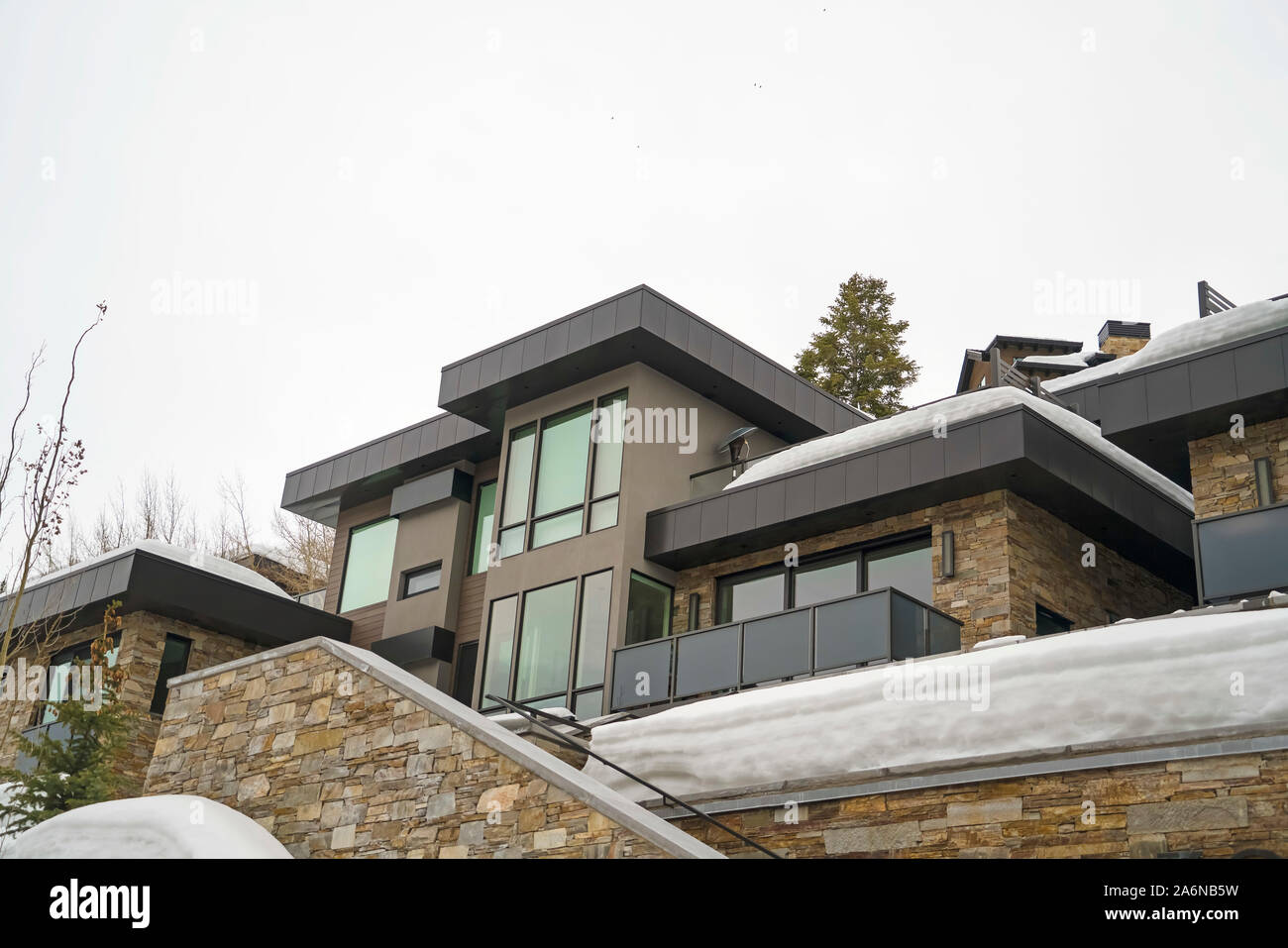Modern home exterior with stone wall and flat roof against white sky in ...
