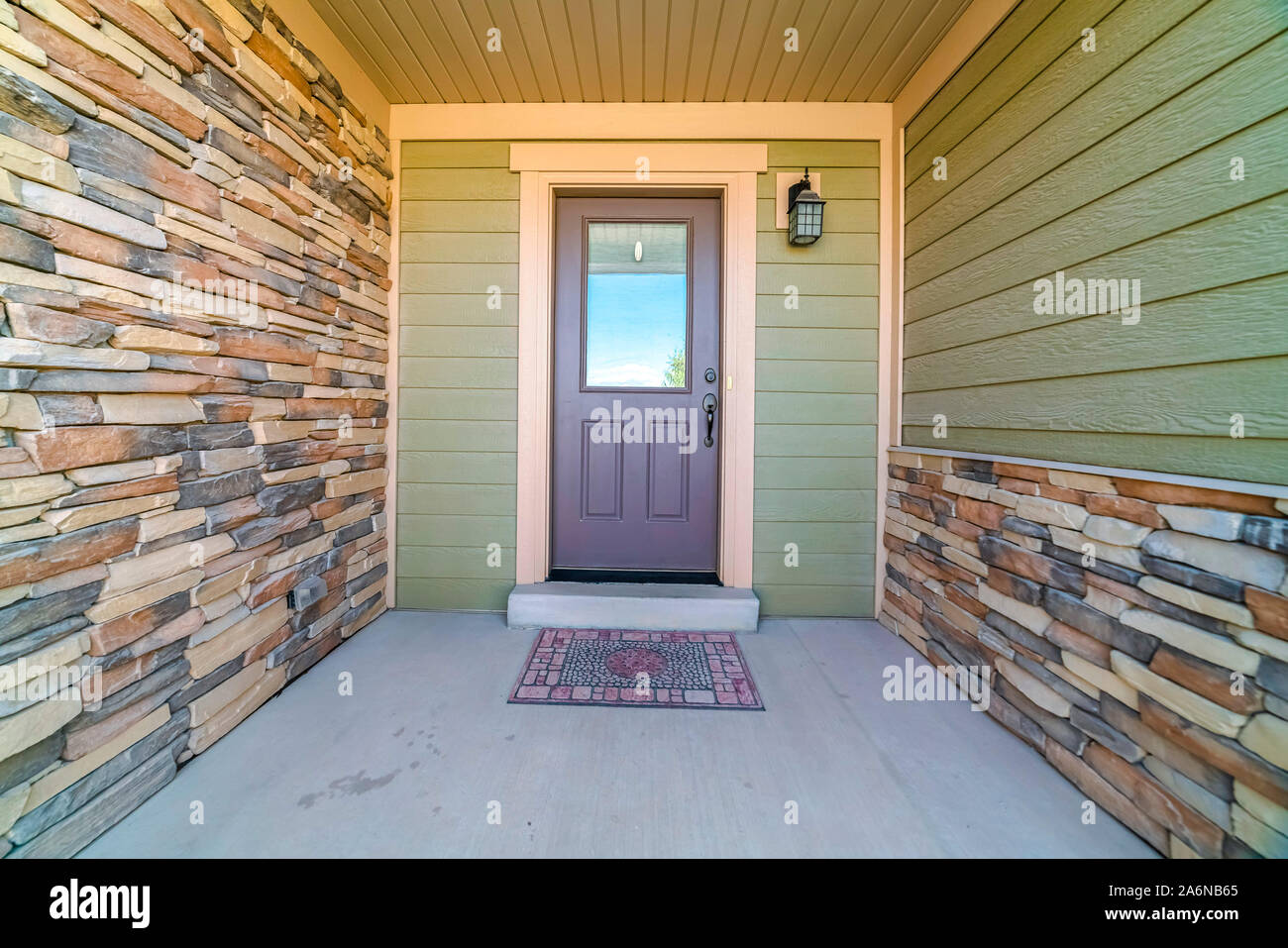 Glass paned front door of a home with green wood wall and stone brick ...