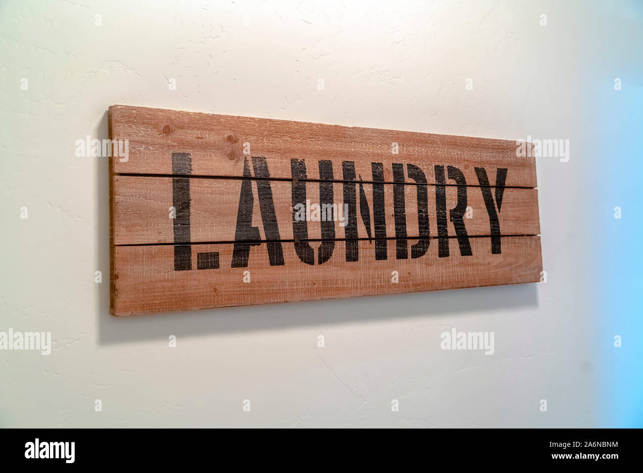 Rustic wooden stencilled Laundry sign on blank white wall Stock Photo ...