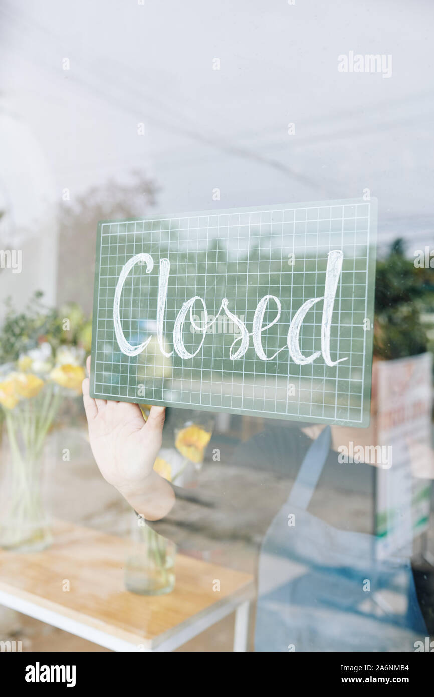 Close-up image of saleswoman turning signboard hanging on glass door ...