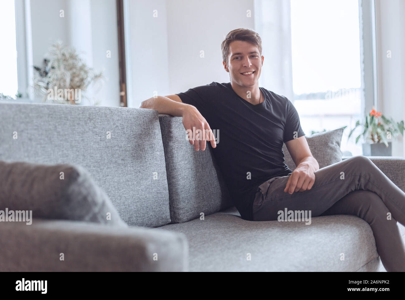 brooding young man sitting on the couch in his living room Stock Photo ...