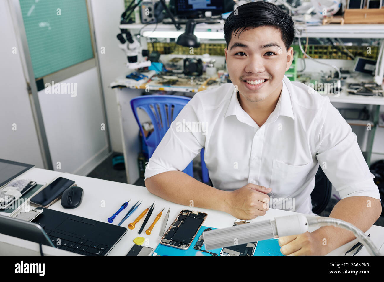 Happy young Asian man enjoying working at smartphone repair shop Stock ...