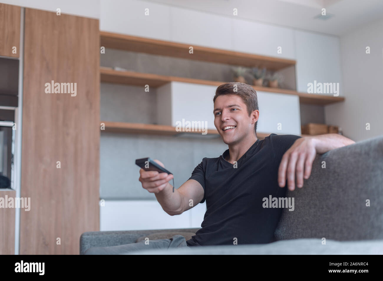 close up. young man turning on TV using his smartphone Stock Photo - Alamy