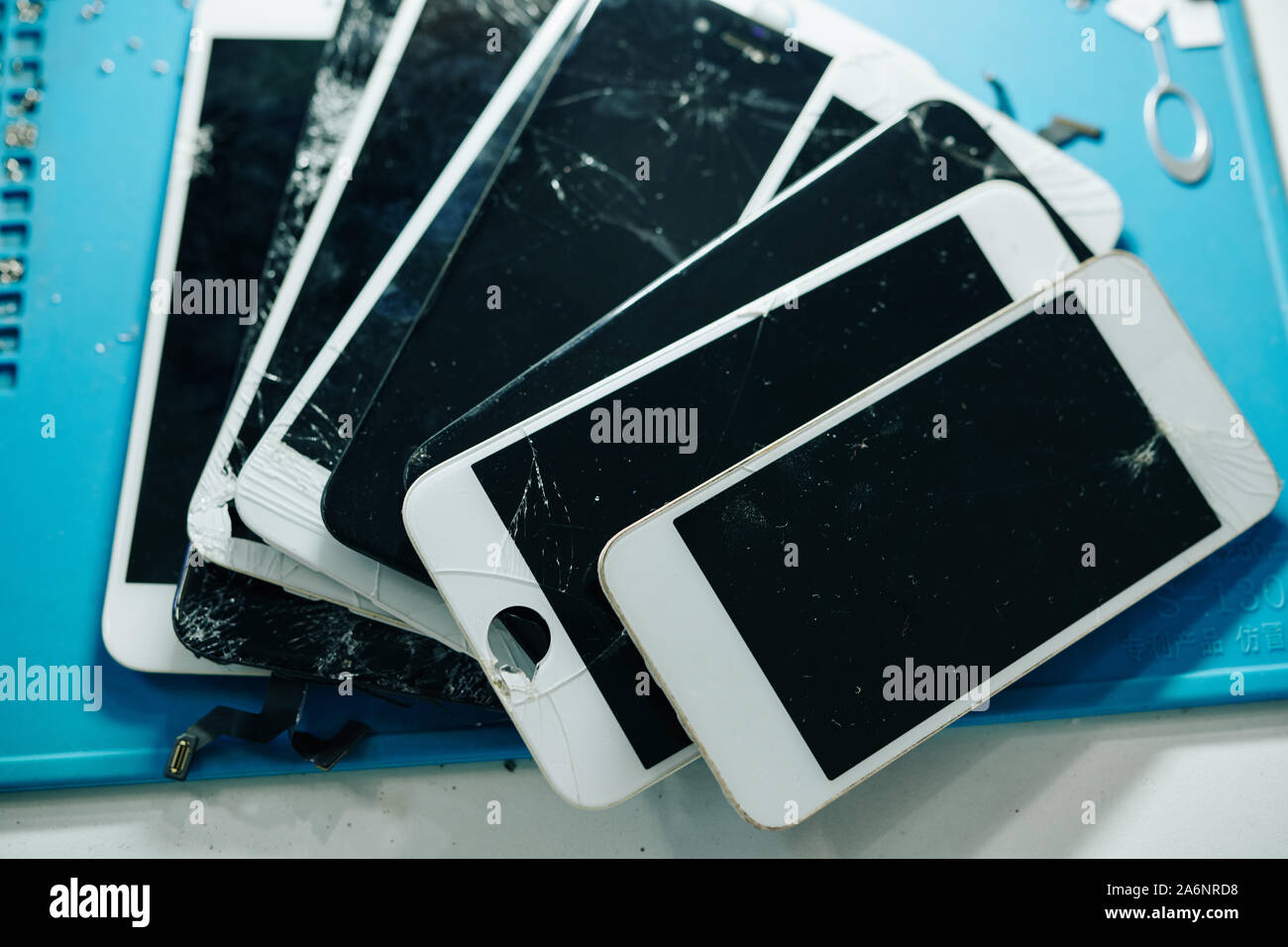 Cracked or broken removed smartphone screens on table of repairman ...