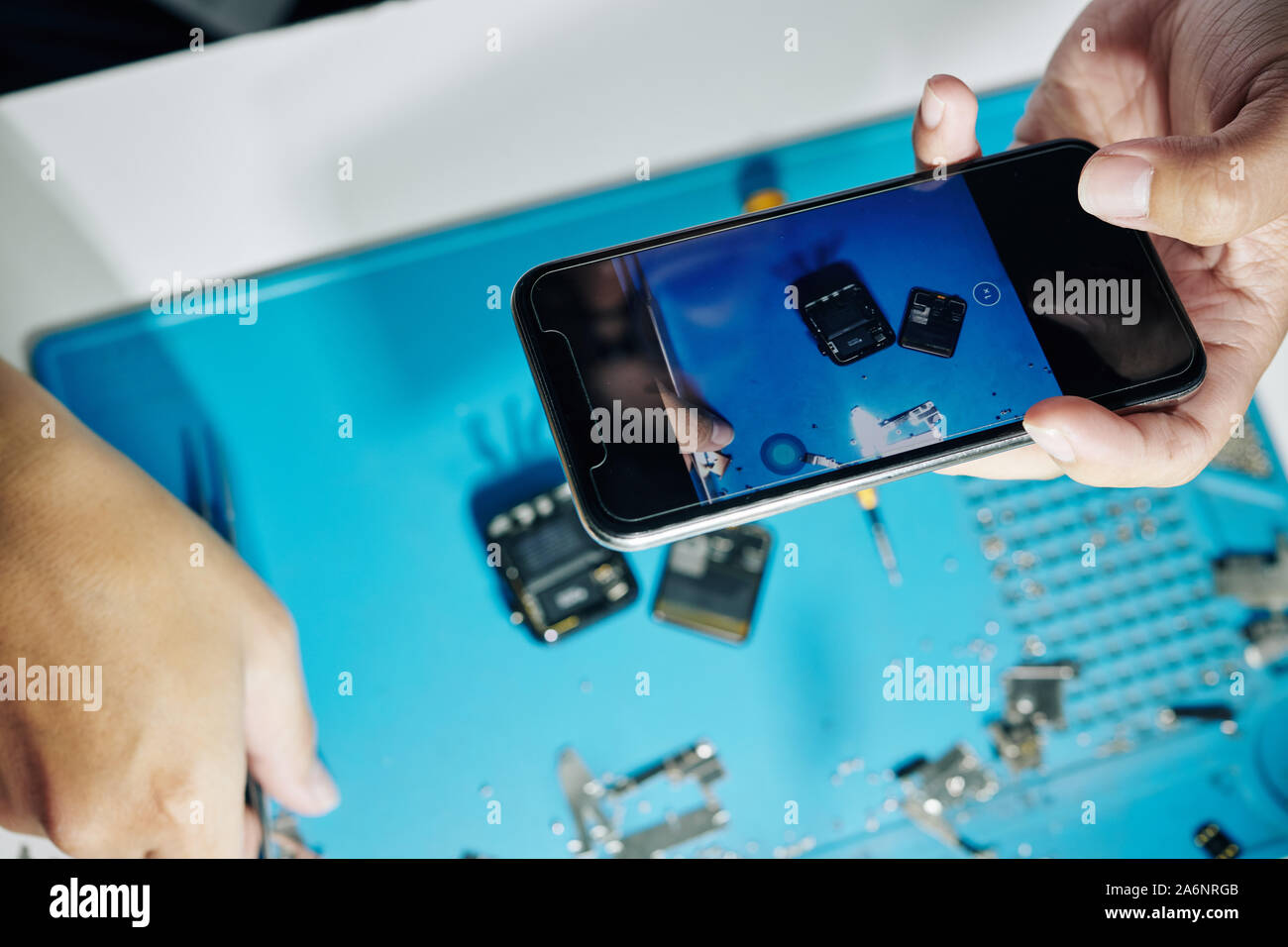 Repairman taking photo of disassembled smartwatch to depict details ...