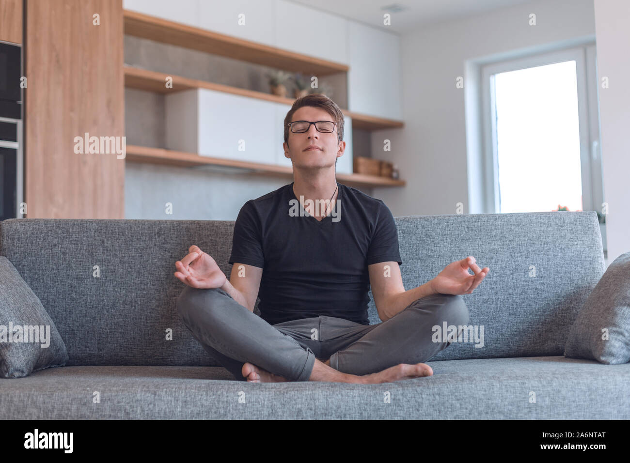 young man sitting in Lotus position on his new sofa Stock Photo - Alamy
