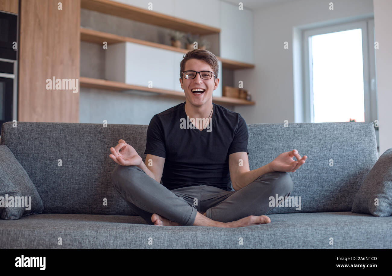 young man sitting in Lotus position on his new sofa Stock Photo - Alamy
