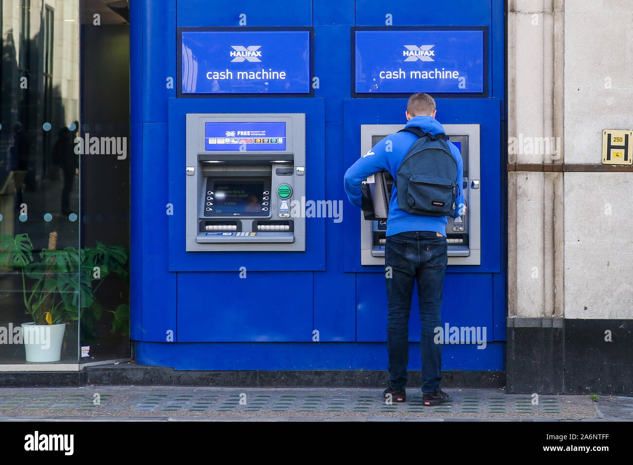 A man uses an ATM machine outside Halifax branch in central London ...
