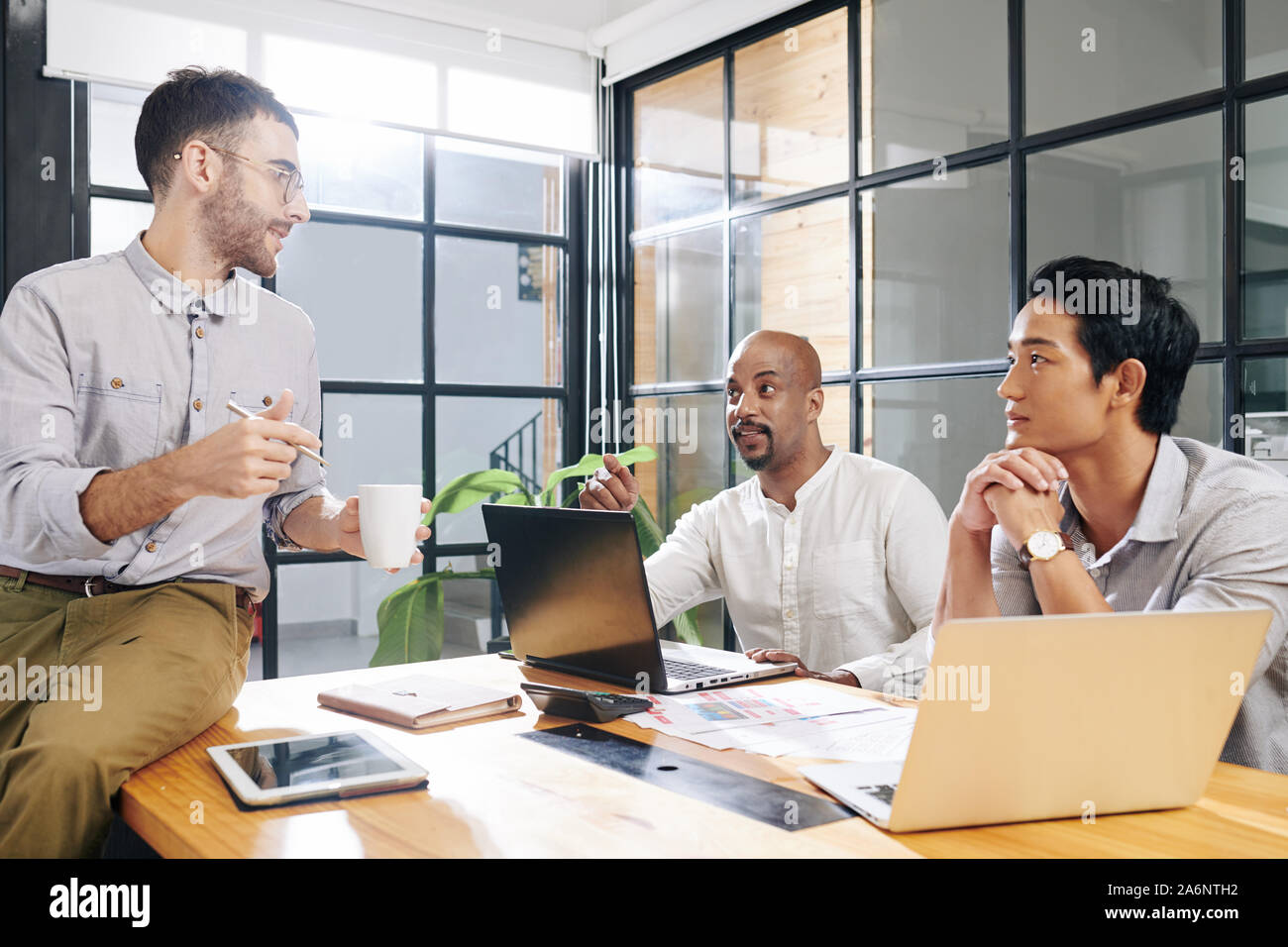 Cheerful business colleagues gathering at meeting room and discussing ...