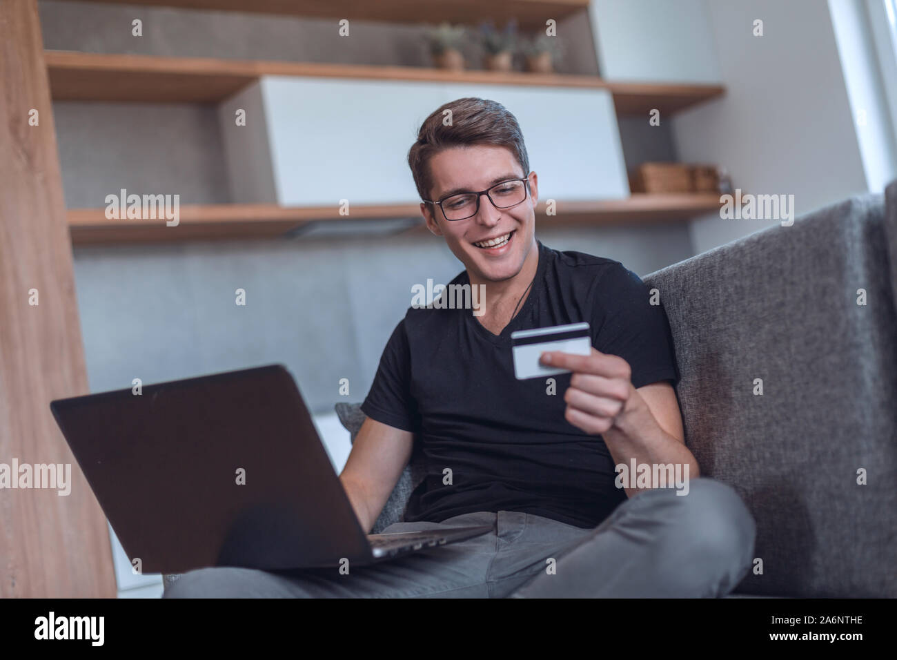 young man using Bank card in his living room Stock Photo - Alamy