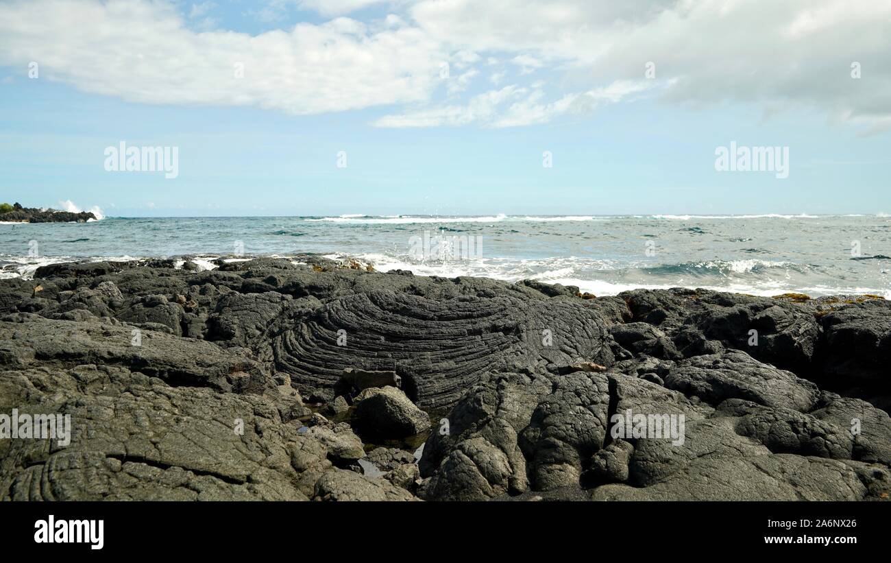black rocky lava shoreline, ocean waves and clear blue sky towards the ...