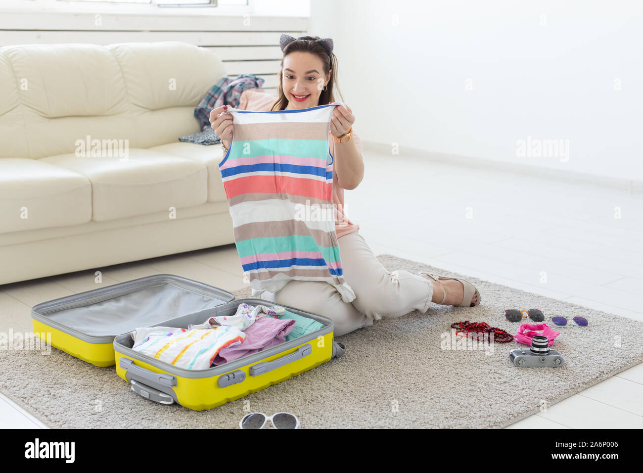 Vacation, journey and holidays concept - woman collecting clothes on ...