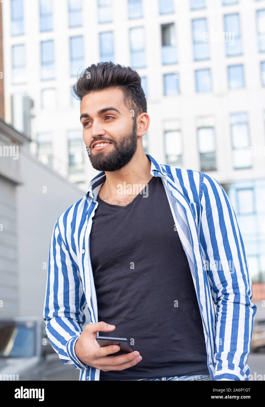 Modern arab young man with mobile phone in the street. Outdoor portrait ...