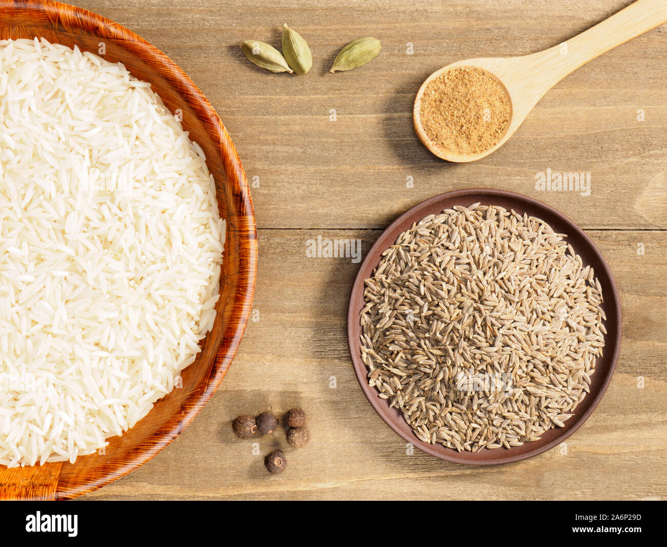 Rice, green cardamom, masala, cumin on brown wooden background. Indian ...