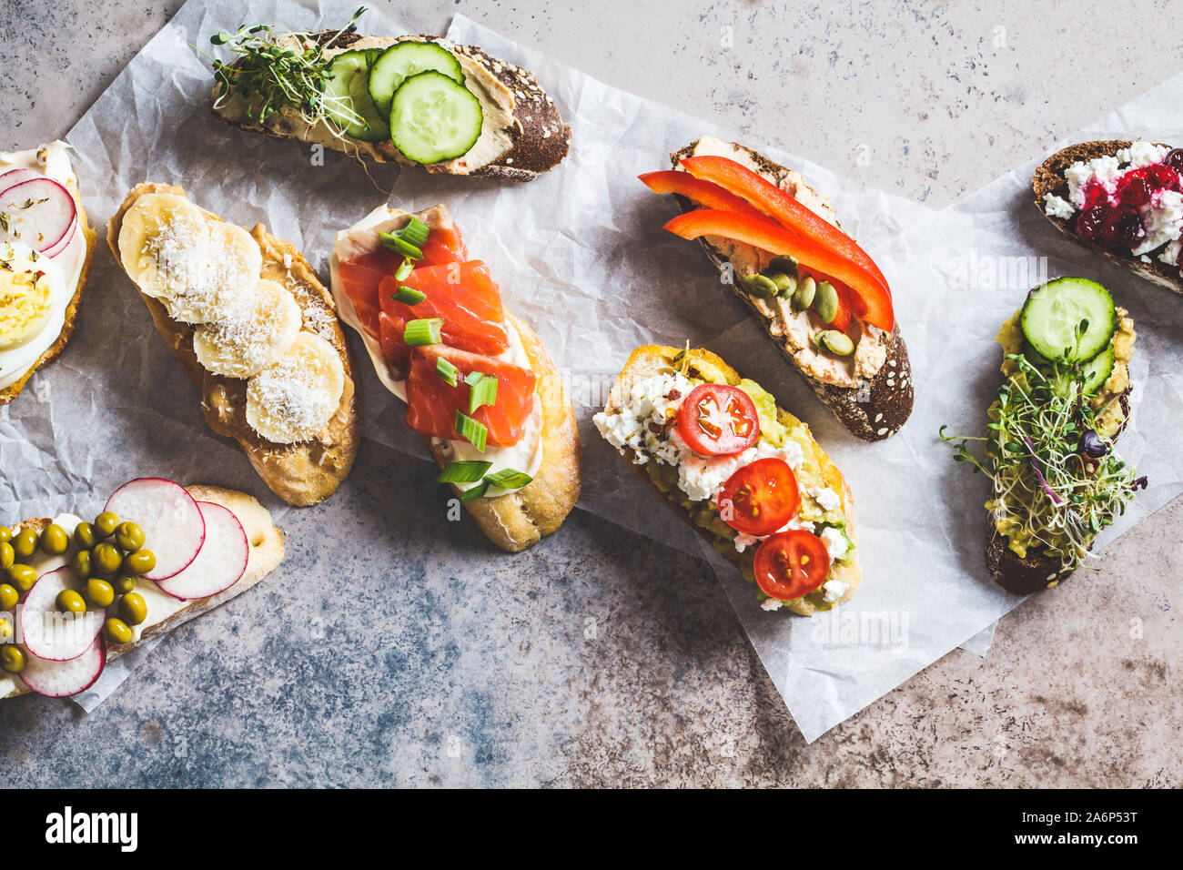 Open toasts with different toppings on gray-brown background. Flat lay ...
