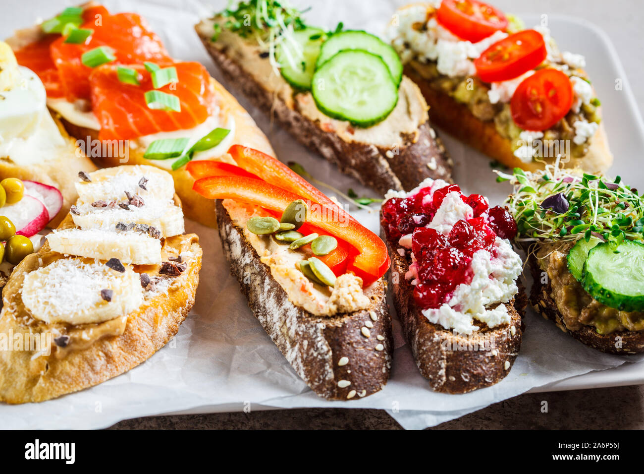 Open toasts with different toppings on gray-brown background. Crostini ...