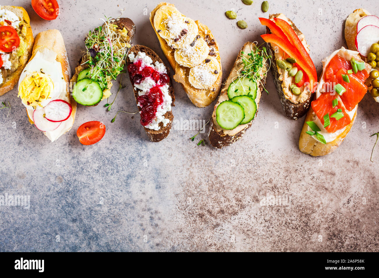 Open toasts with different toppings on gray-brown background. Flat lay ...
