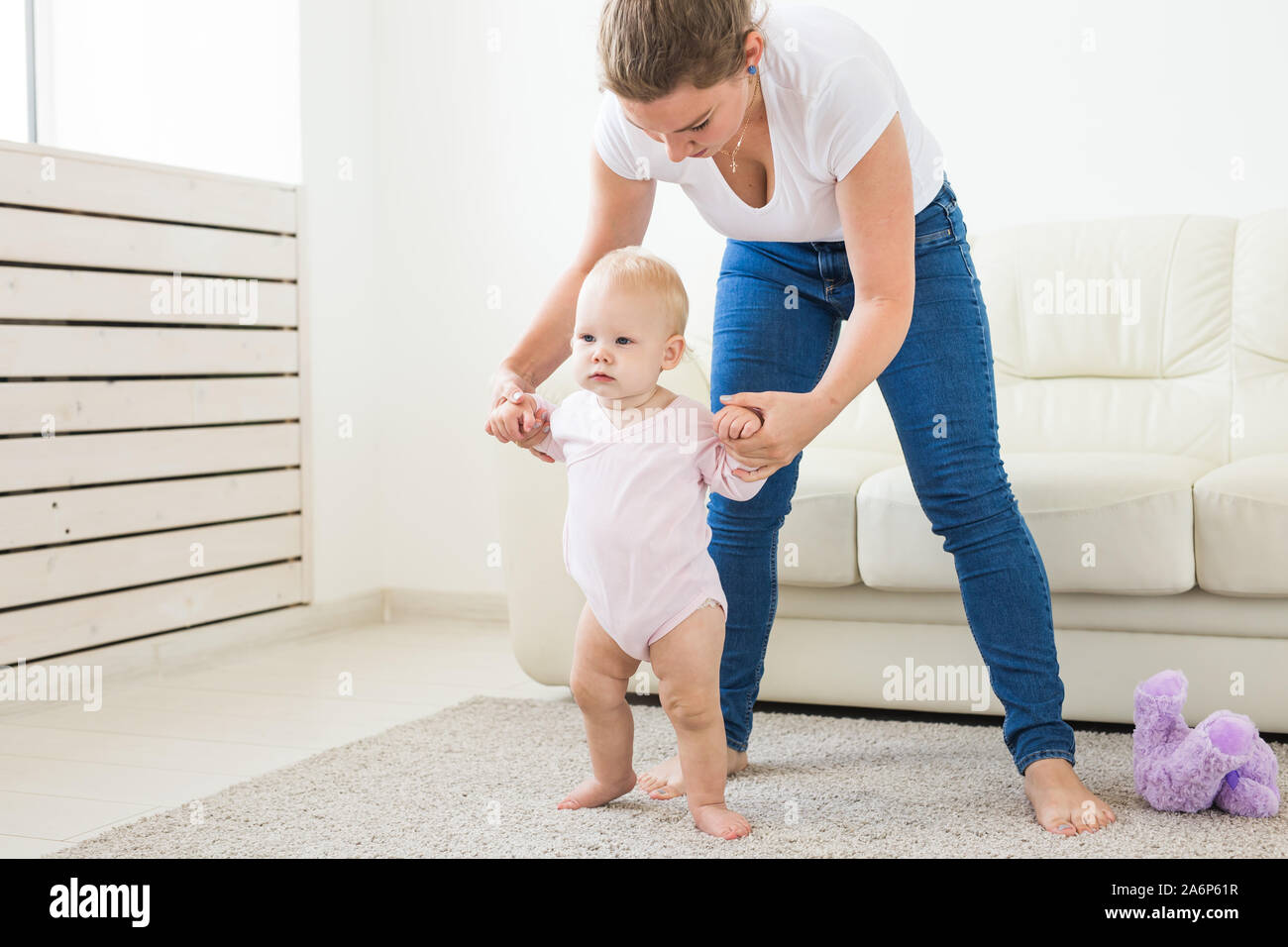 Little baby girl first steps with the help of mom Stock Photo - Alamy