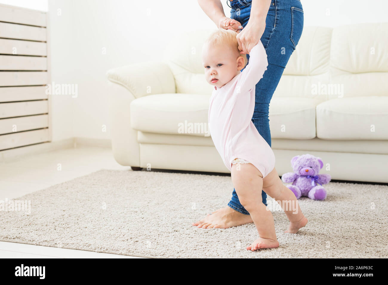 Little baby girl first steps with the help of mom Stock Photo - Alamy