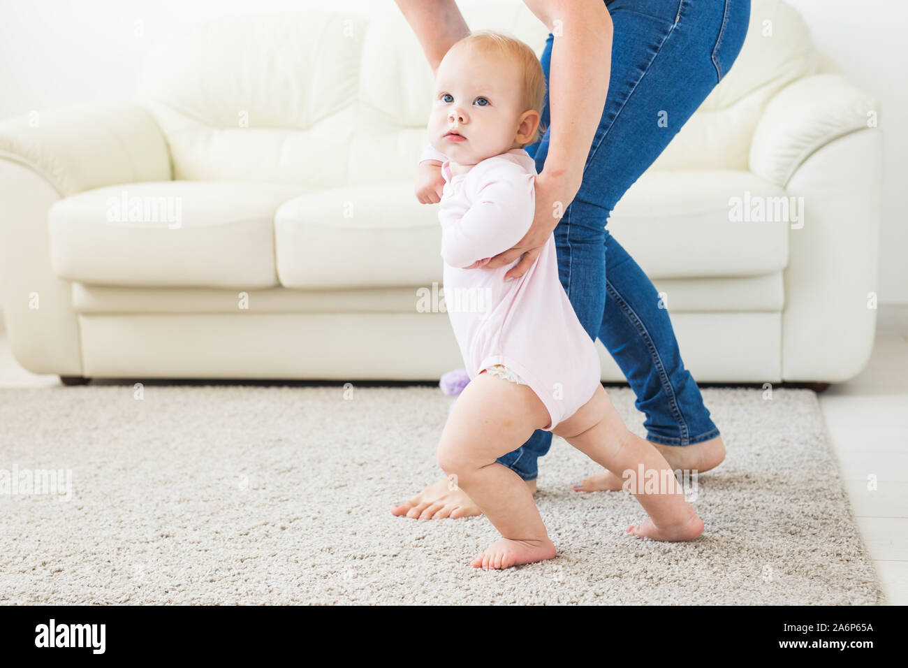 Little baby girl first steps with the help of mom Stock Photo - Alamy