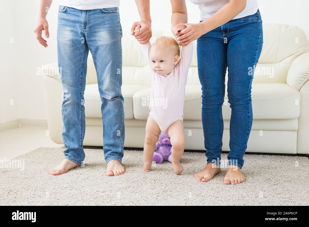Little baby girl first steps with the help of mom and dad Stock Photo ...