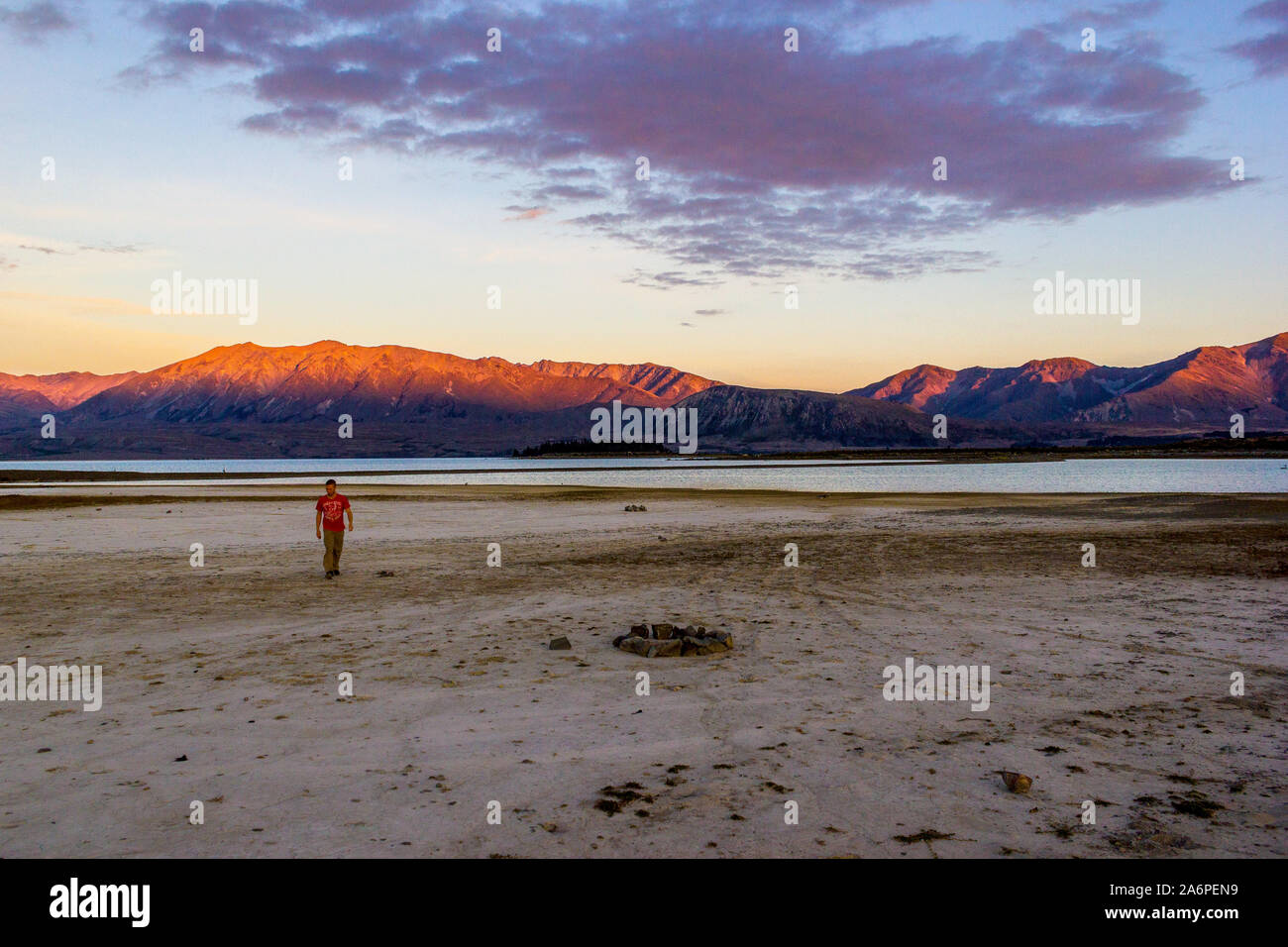 young causacian man walking on beach at beautiful Lake Tekapo with ...