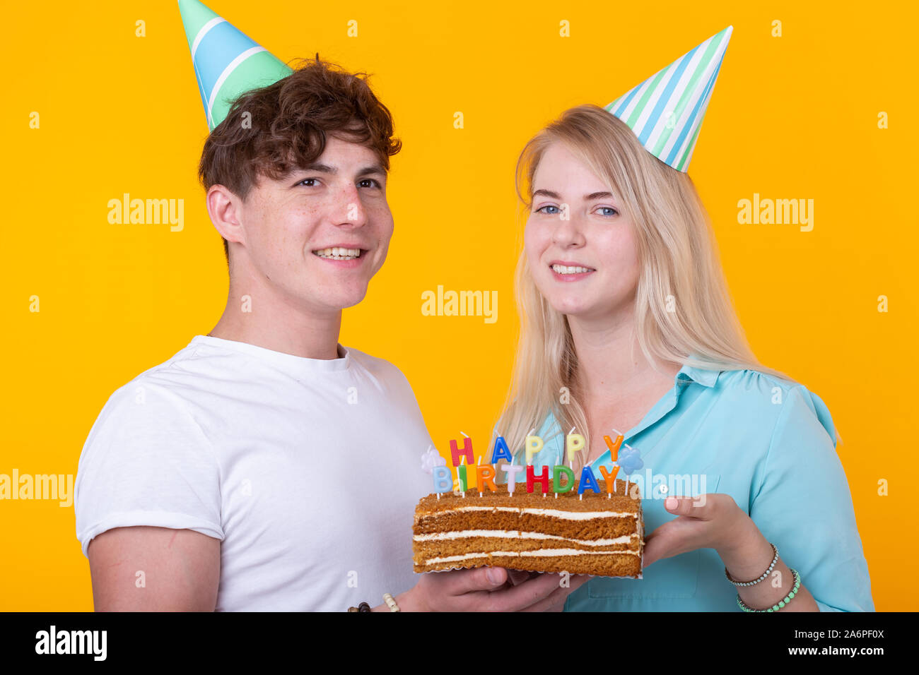 Cheerful young couple charming guy and cute girl in paper hats make ...
