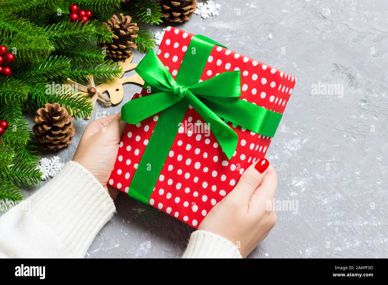 Top view of a woman holding a gift box in her hands on festive cement ...