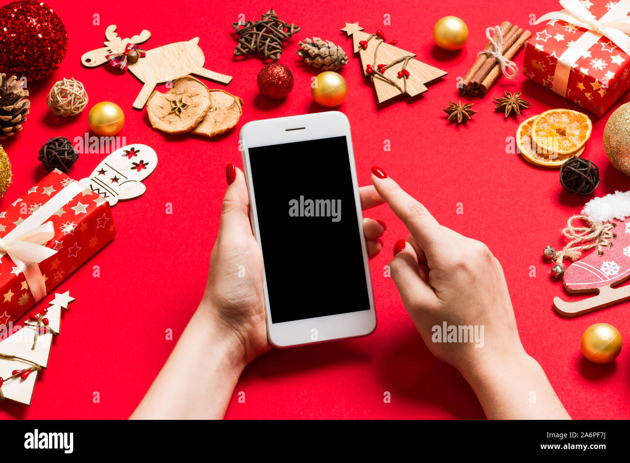 Top view of phone in female hand on festive red background. Christmas ...