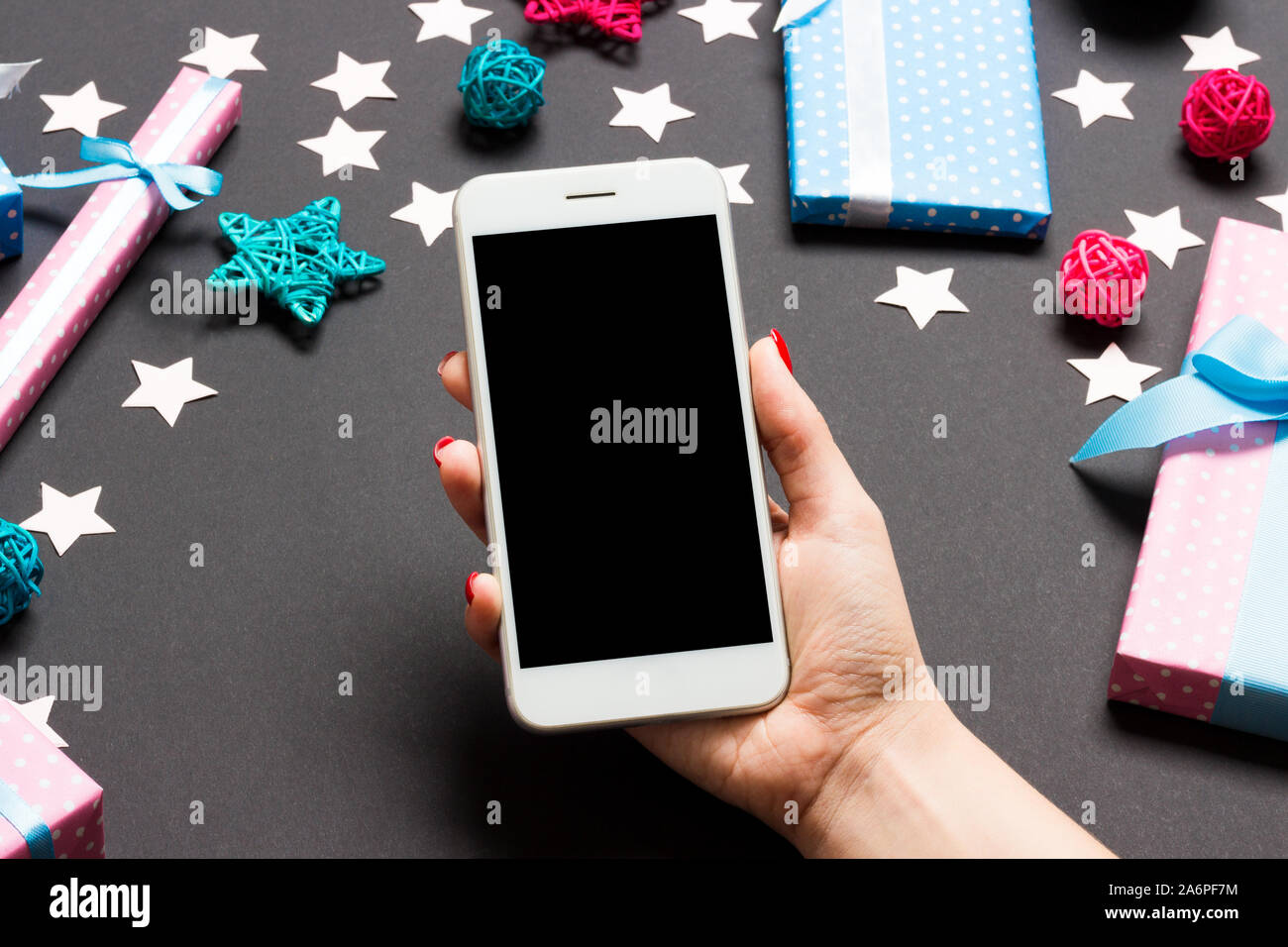 Top view of phone in female hand on festive black background. Christmas ...