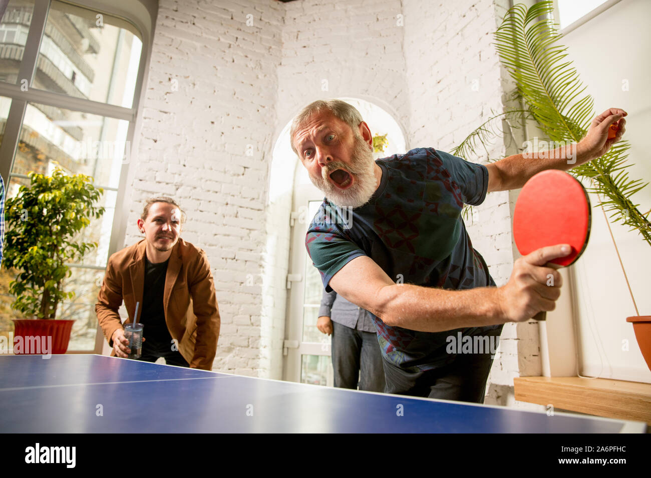 Young people playing table tennis in workplace, having fun. Friends in ...