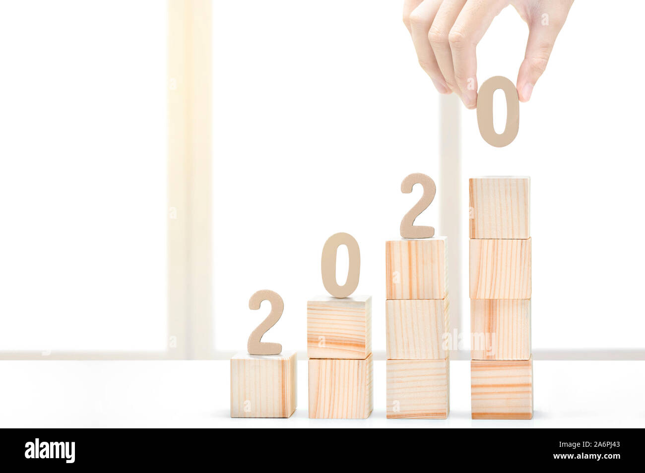 Hand put the number 0 to make 2020 on stairs of wooden block toy on the ...