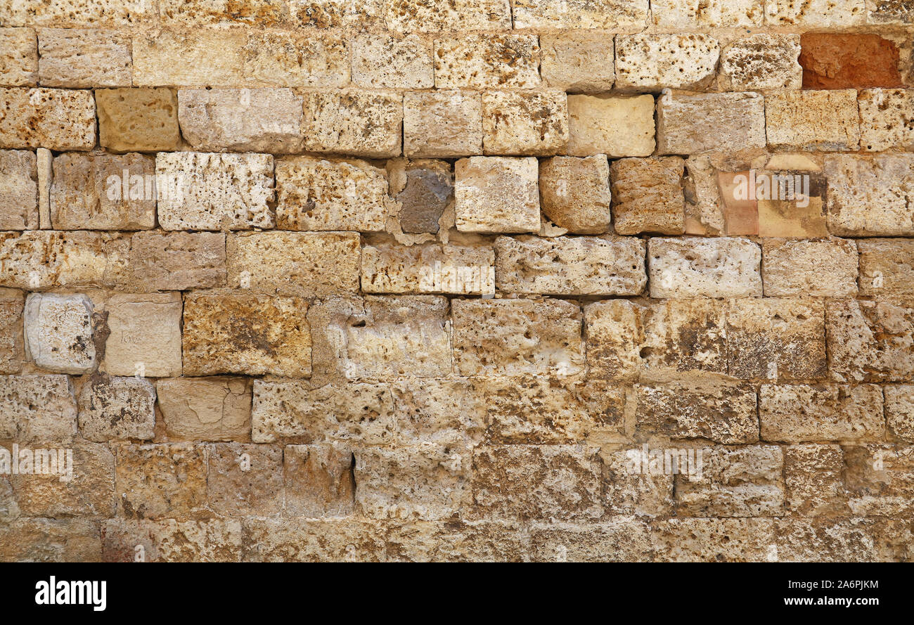 Wall of white and brown antique limestone stone brick blocks, close up ...