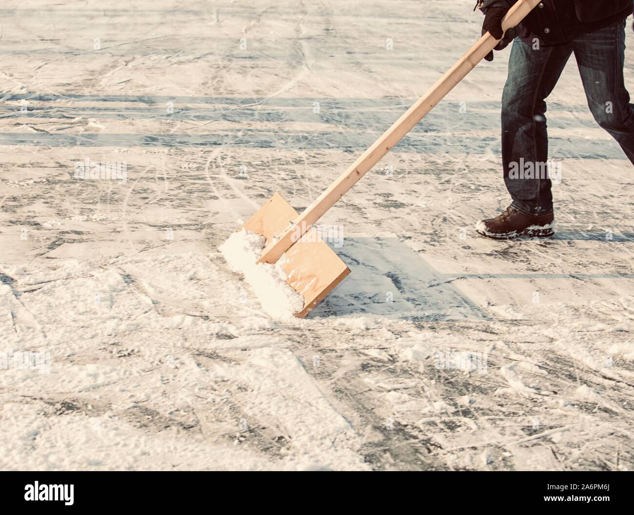 Shoveling snow with wooden shovel from ice for speed ice skating with ...