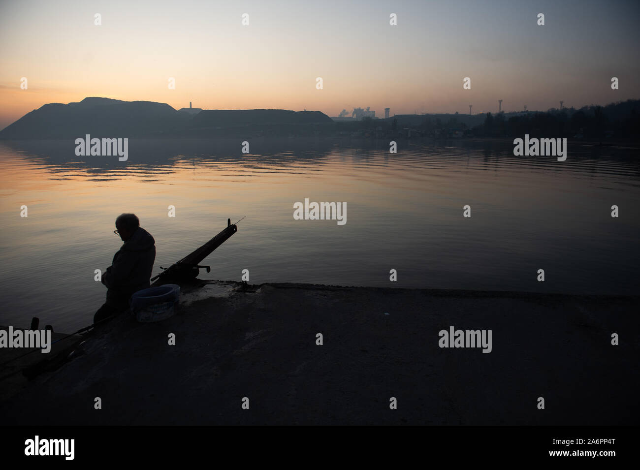 A man fishing at the shores of the Azov sea in Mariupol.The two large ...
