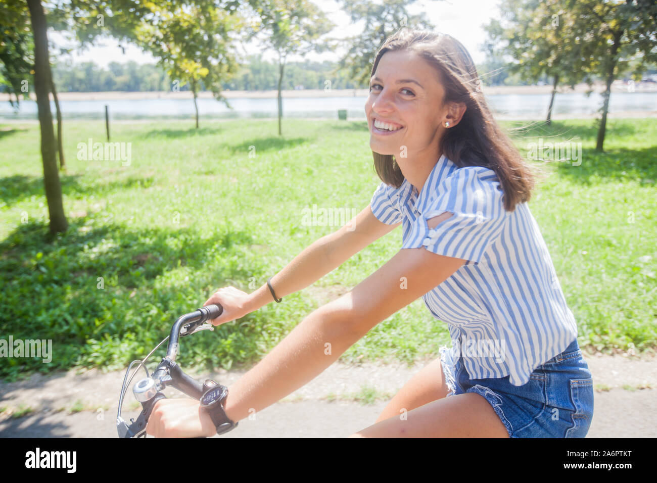 Smiling girl enjoying summer day with bicycle in nature. Beautiful girl ...