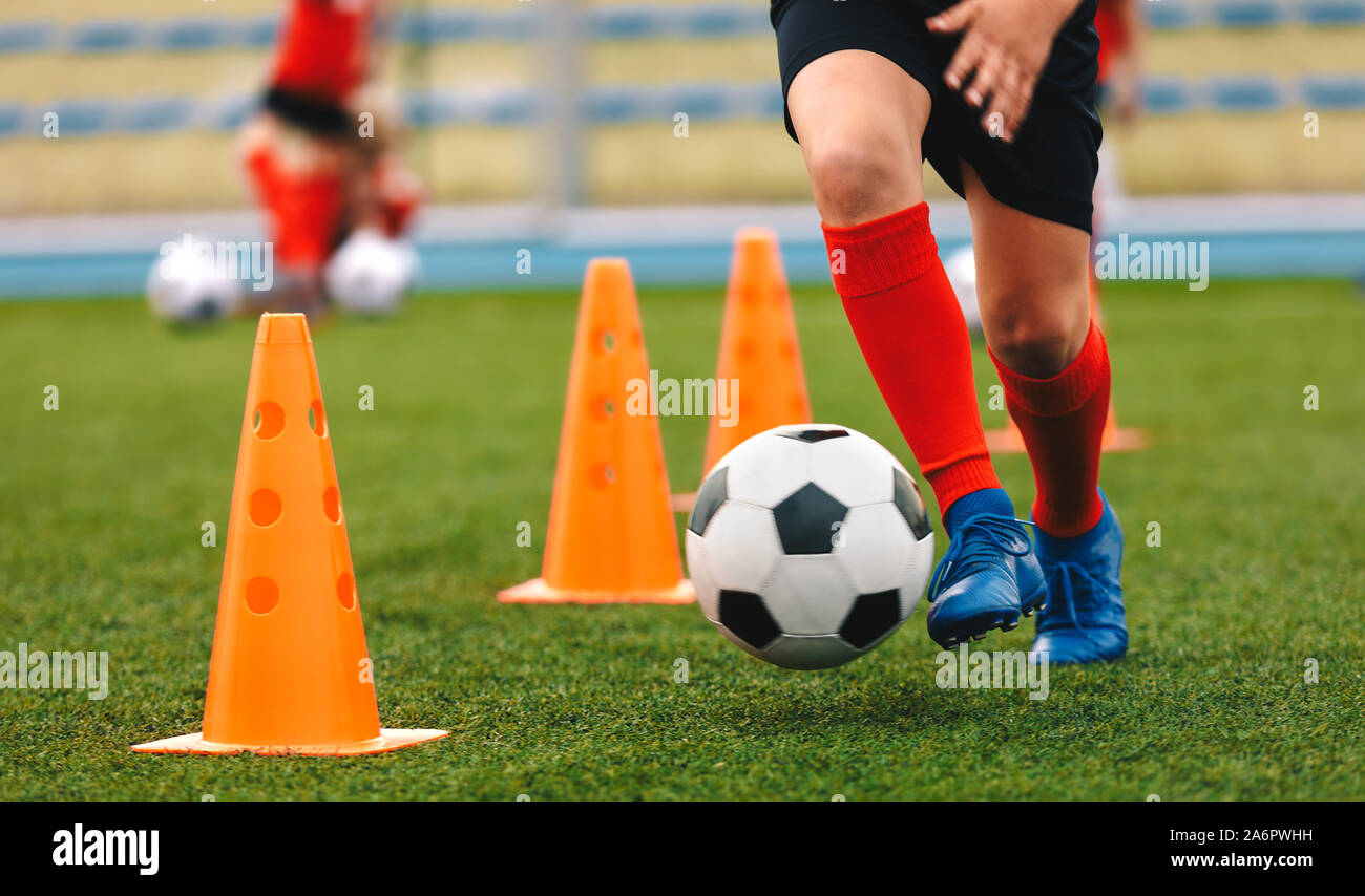 Footballer dribbling ball on training between orange cones. Young ...