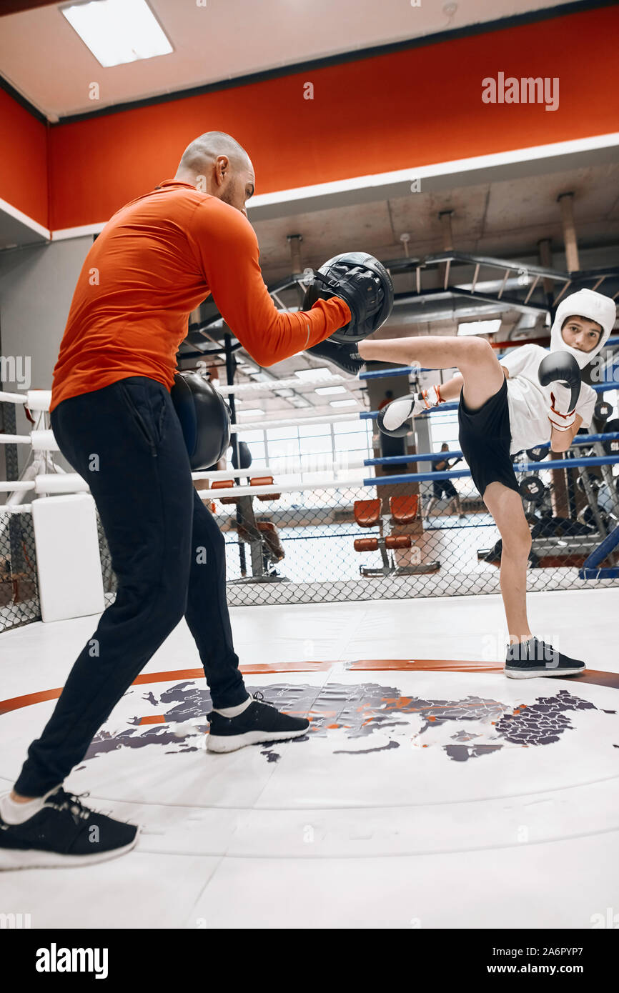 Young hardworking kickbox fighter hitting mitts with his coach, boy ...