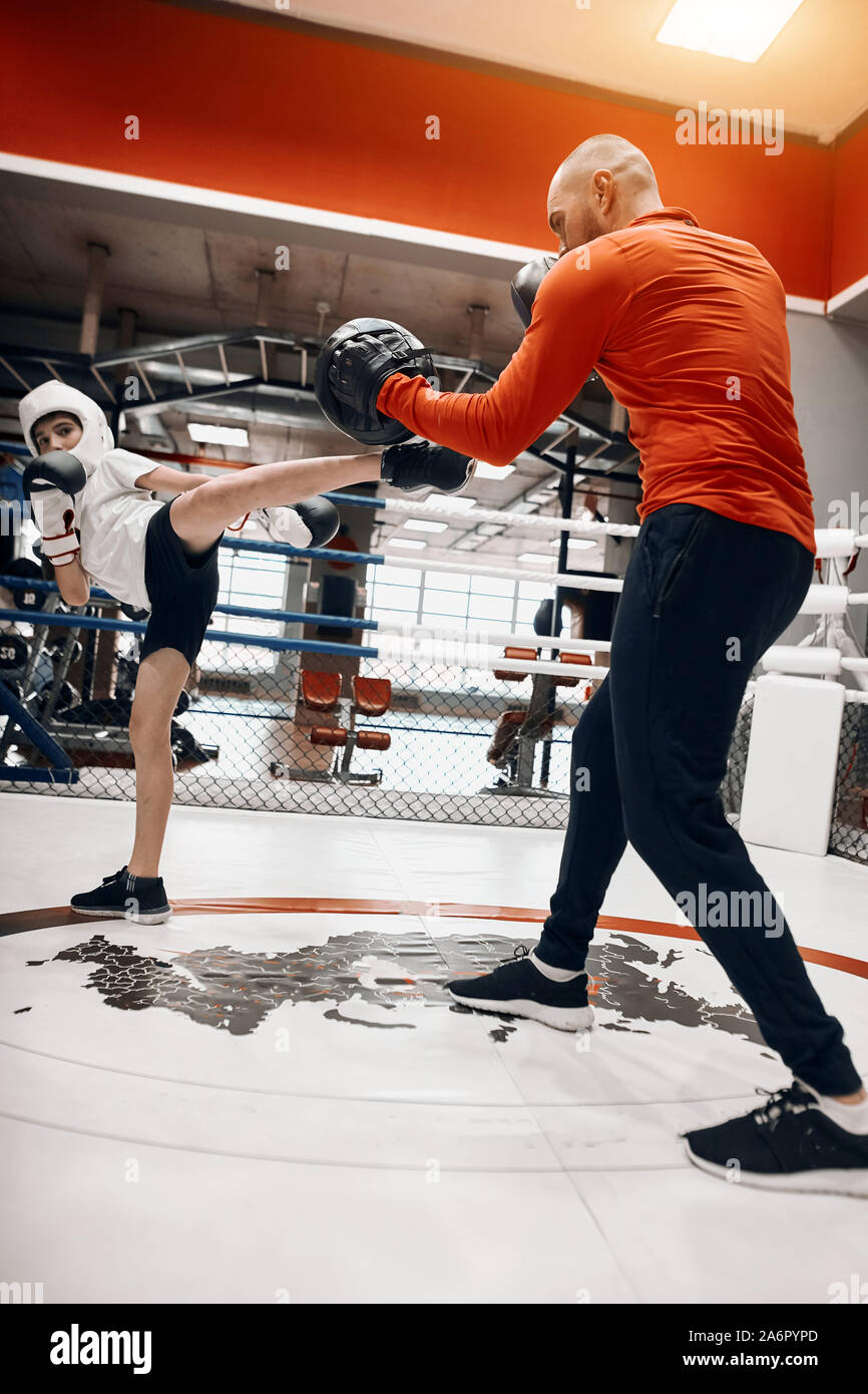 little boy practising kickboxing with his coach, full length photo ...