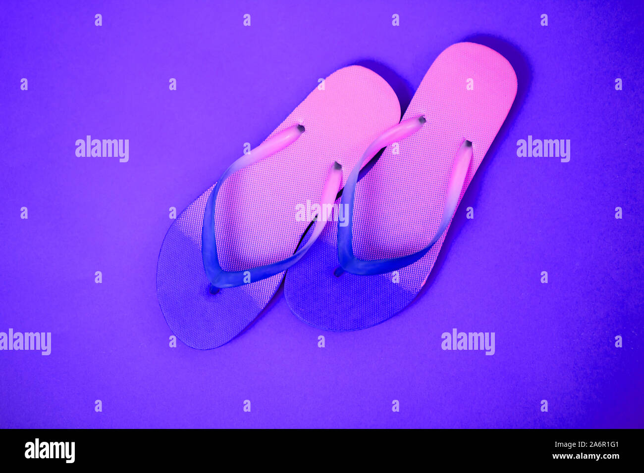 A studio photo of pink sandals. Colorful flip flops isolated on purple ...