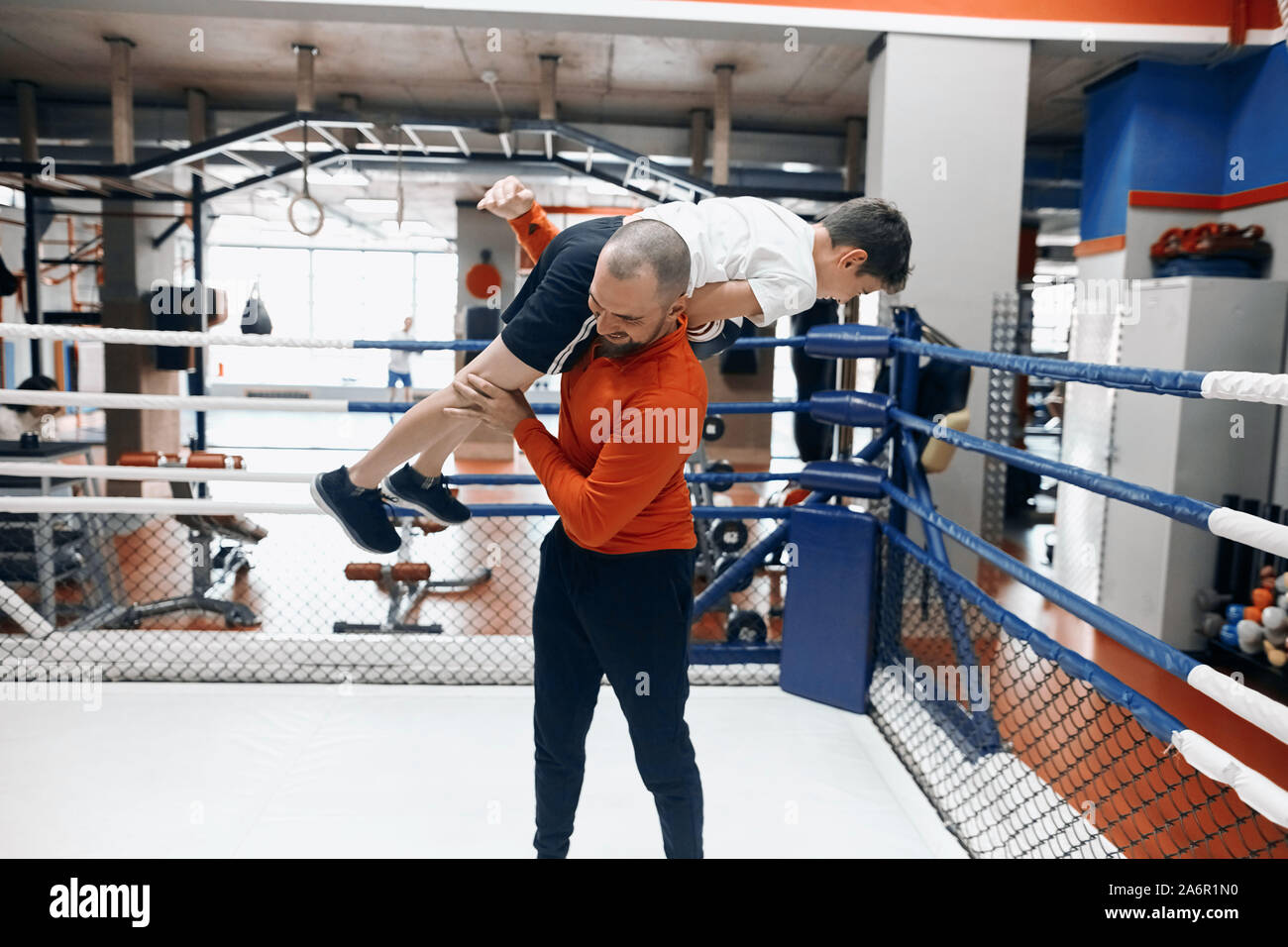 cheerful positive personal trainer lifting his student, makes him ...