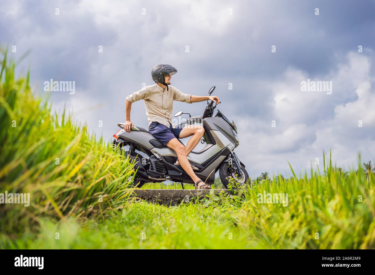 Male traveler on a bike among a rice field. Tourist travels to Bali ...