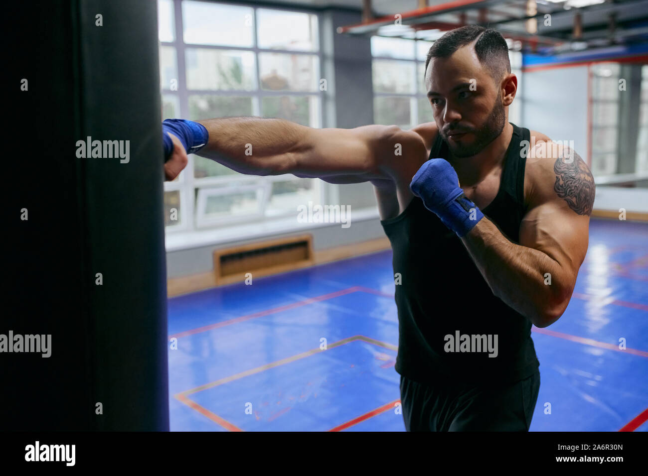 Young man punching boxing bag, close up photo. guy concentrated on ...