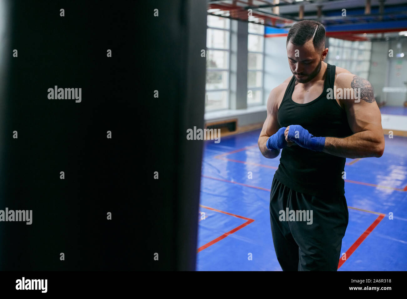 young sportsman preparing for boxing while standing next to punching ...